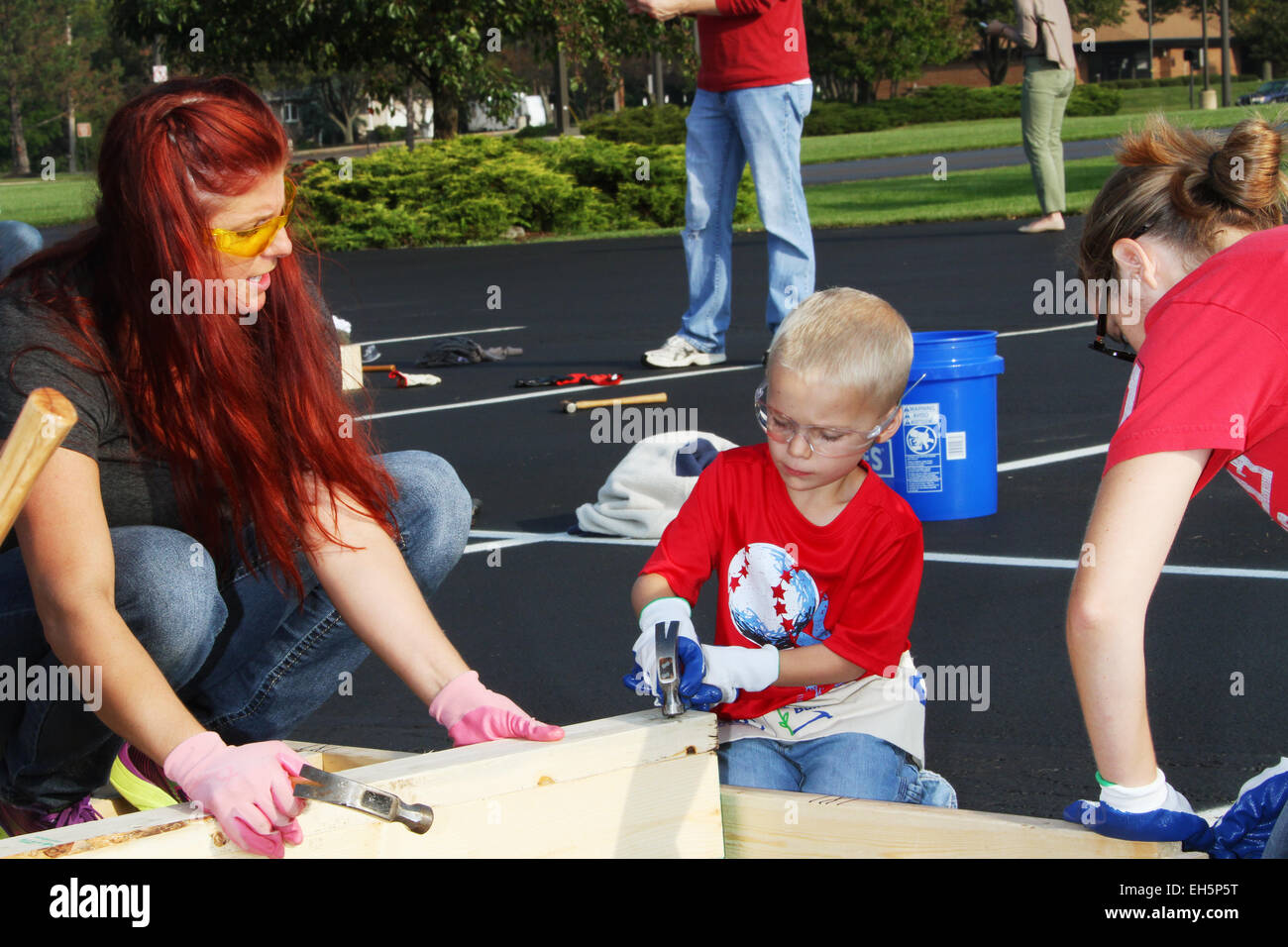 Two women and a boy. Volunteer people building a house wall panel ...