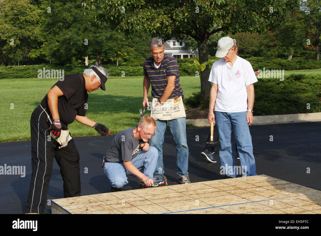 Volunteer men building a house wall panel. Habitat For Humanity parking ...