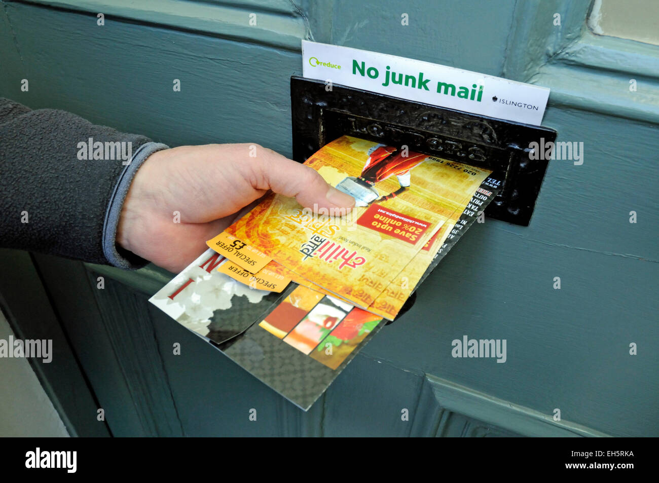 Mans hand pushing junk mail through lettebox with No Junk Mail sign ...