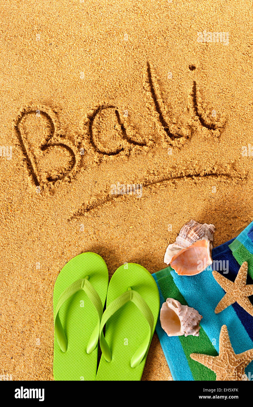 The word Bali written on a sandy beach, with beach towel, starfish and ...