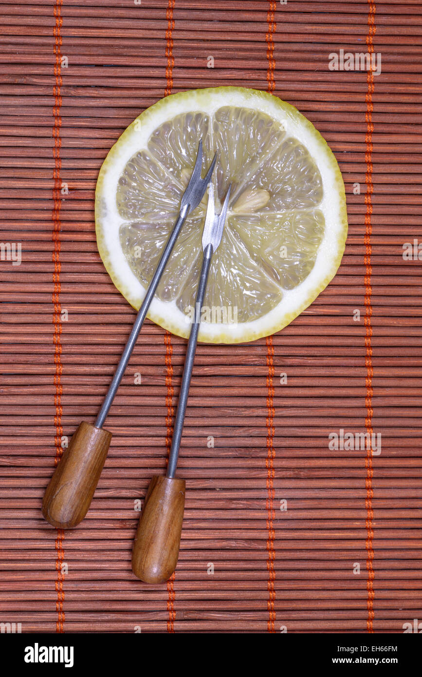 Sliced fresh lemon with forks on a nice wicker carpet as background ...