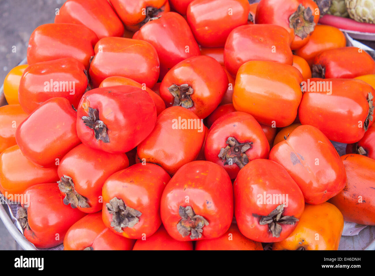 A pile of red persimmons, at a market Stock Photo - Alamy