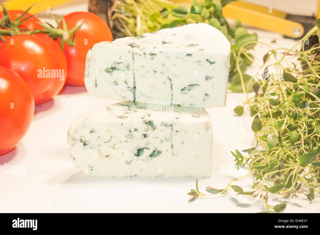 Two triangles of blue cheese, between thyme and tomatoes Stock Photo ...