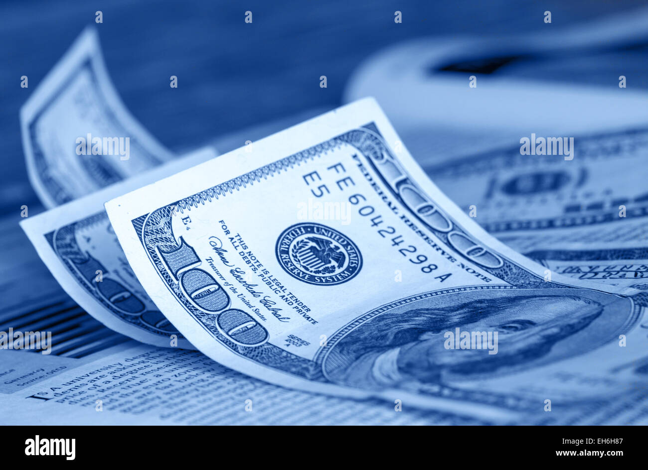 Blue tinted image of selective focus shot. One hundred dollar bills on ...