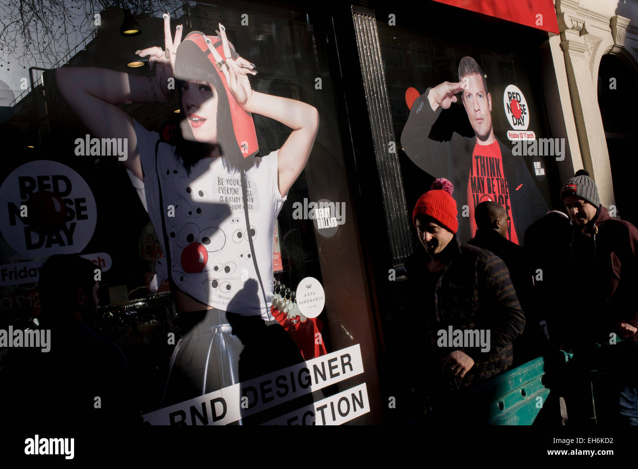 Shoppers walk beneath TK Maxx shop posters for the Red Nose Day charity ...