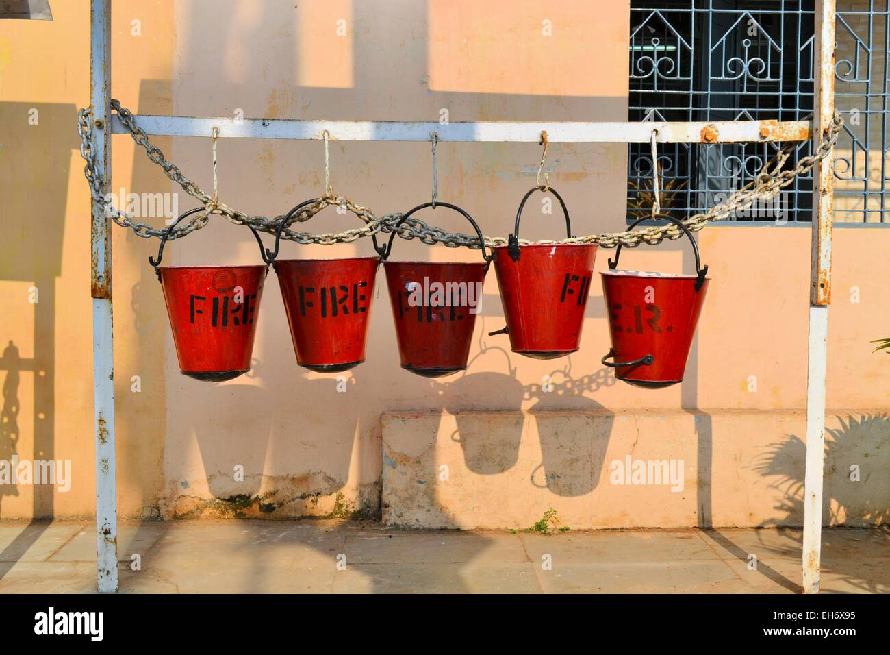 Five fire buckets hanging on a wall in India Stock Photo - Alamy