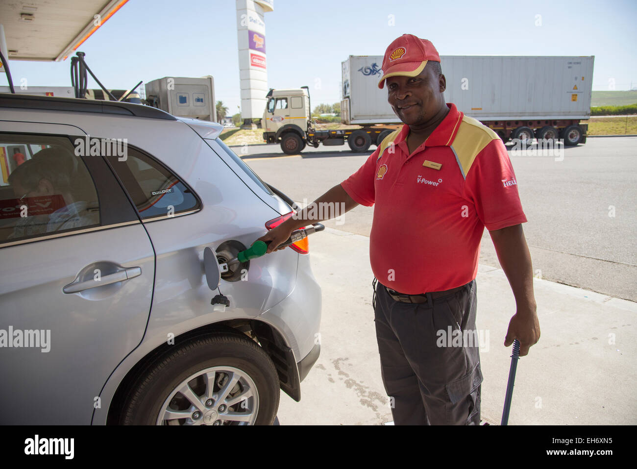Petrol pump attendant serving fuel in a South African filling station ...