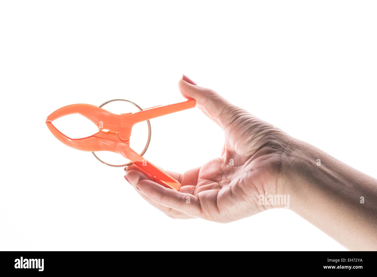 Female hand with manicure holds plastic clip on a white background ...