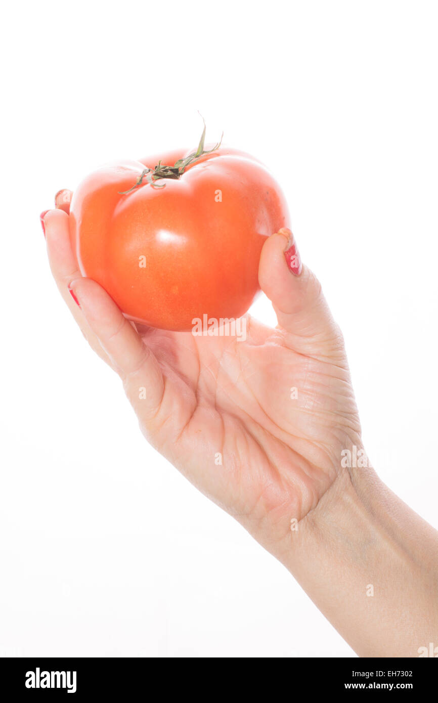 Woman's hand with red varnish shows tomato on a white background Stock ...