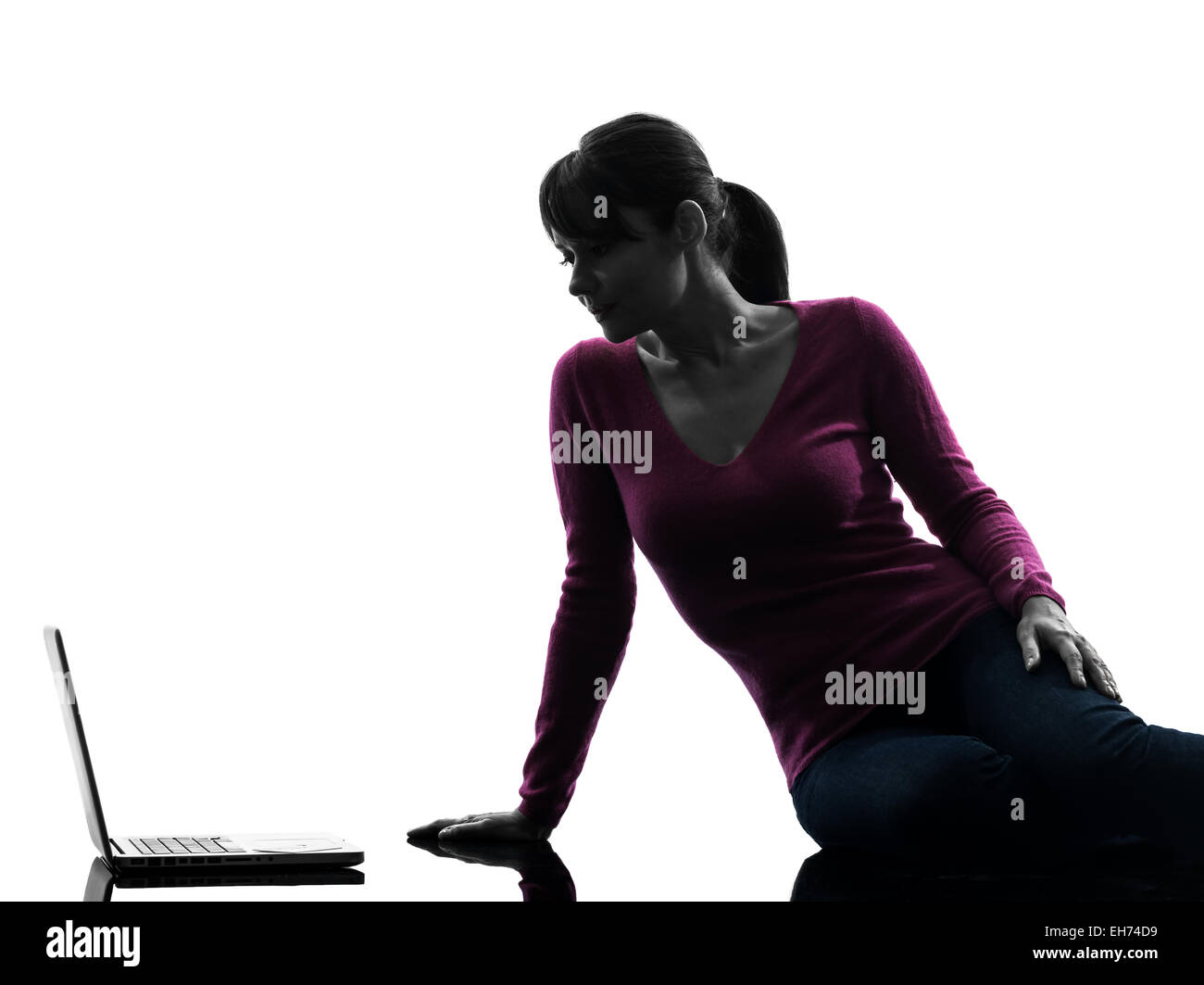 one woman serious computing laptop computer in silhouette studio ...