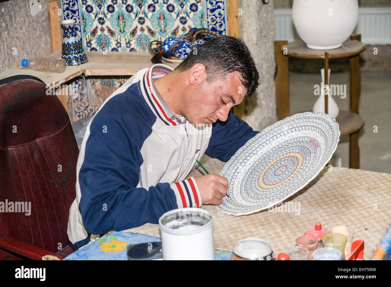 Local craftsman concentrating working on carefully painting a detailed ...