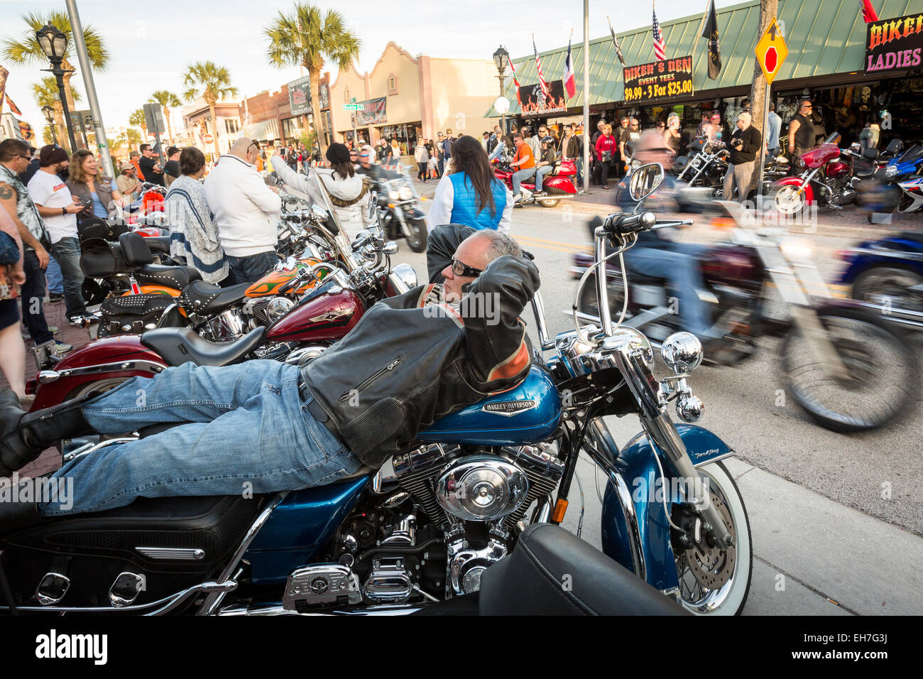 A biker rests on his Harley-Davidson as others ride past along Main ...