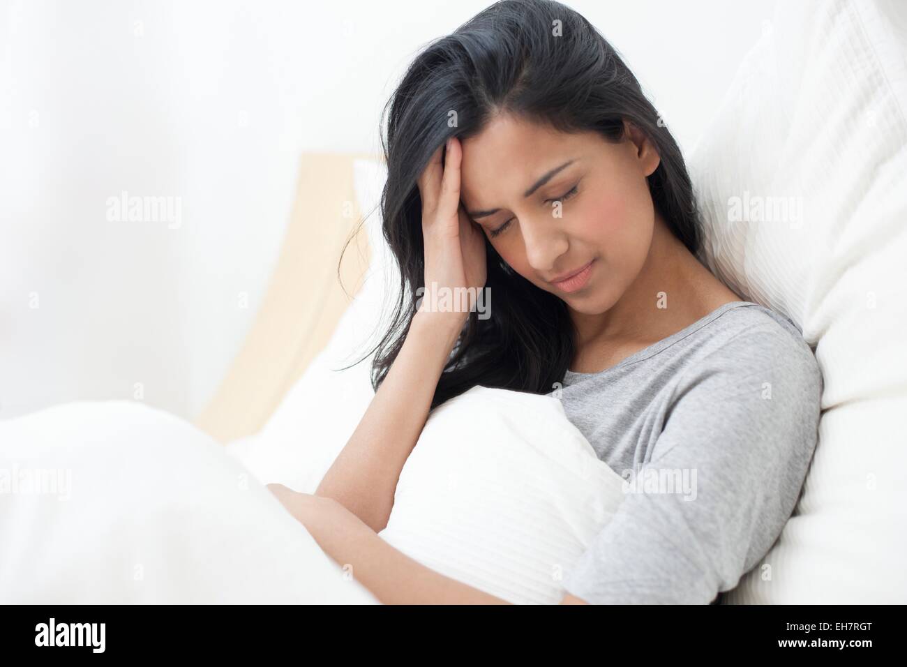 Woman in bed touching her head Stock Photo - Alamy