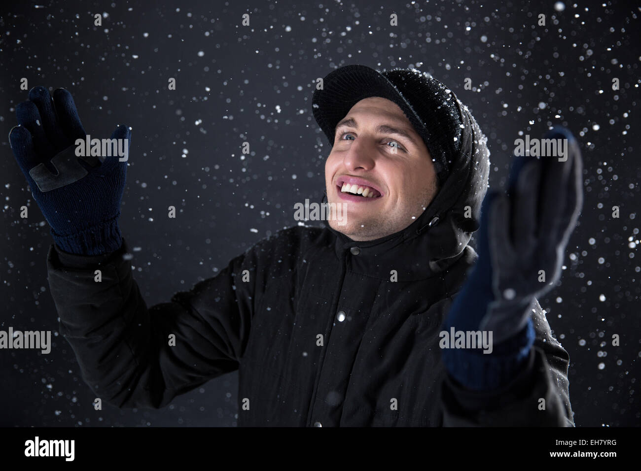 Happy man enjoys snow over black background Stock Photo - Alamy