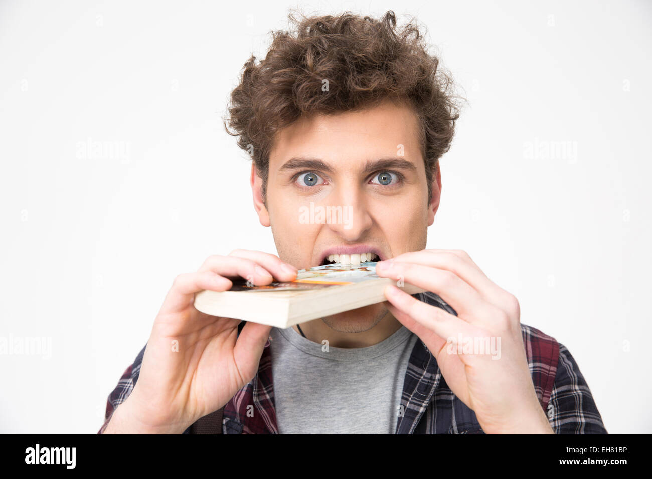 Handsome young man biting book over gray background Stock Photo - Alamy