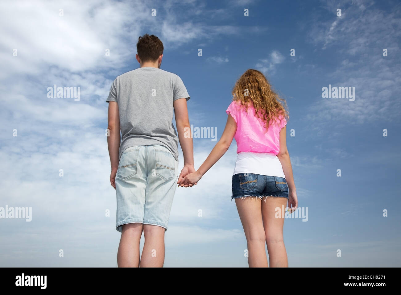 Young couple stays in front of cloudy blue sky Stock Photo - Alamy