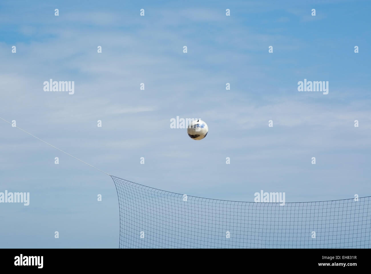 Soccer ball high up in the air against blue sky and net Stock Photo - Alamy