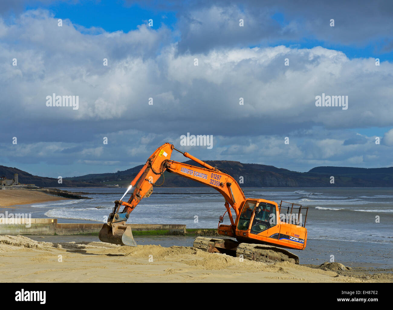 Levelling the beach with a JCB digger, Lyme Regis, Dorset, England UK ...
