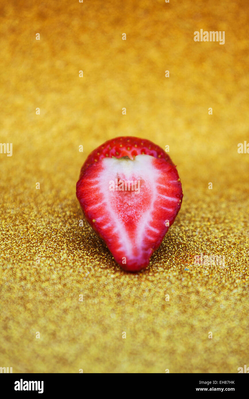 An open strawberry on a golden glittery background Stock Photo - Alamy