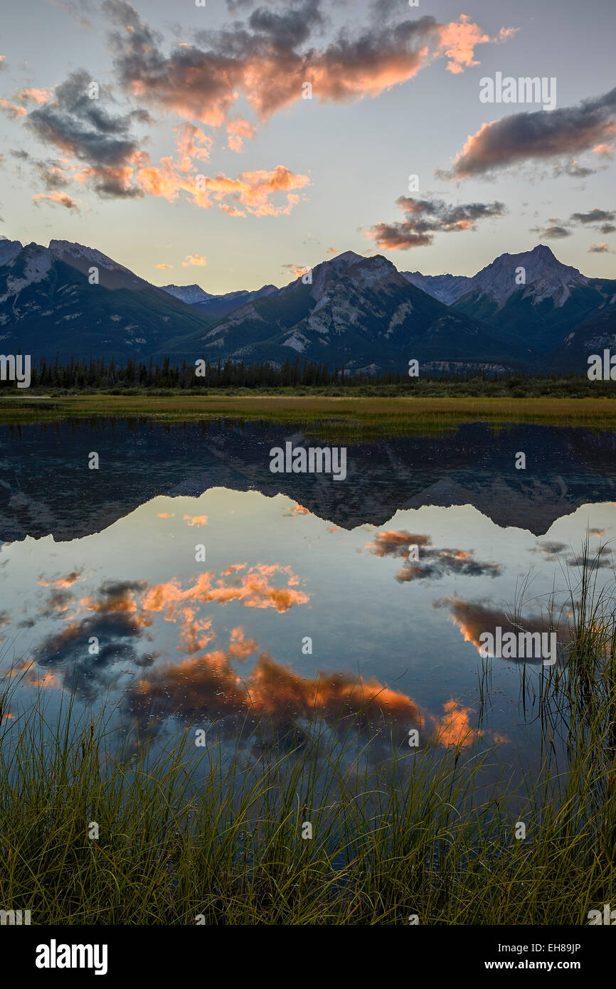Orange clouds at sunset reflected in a lake, Jasper National Park ...