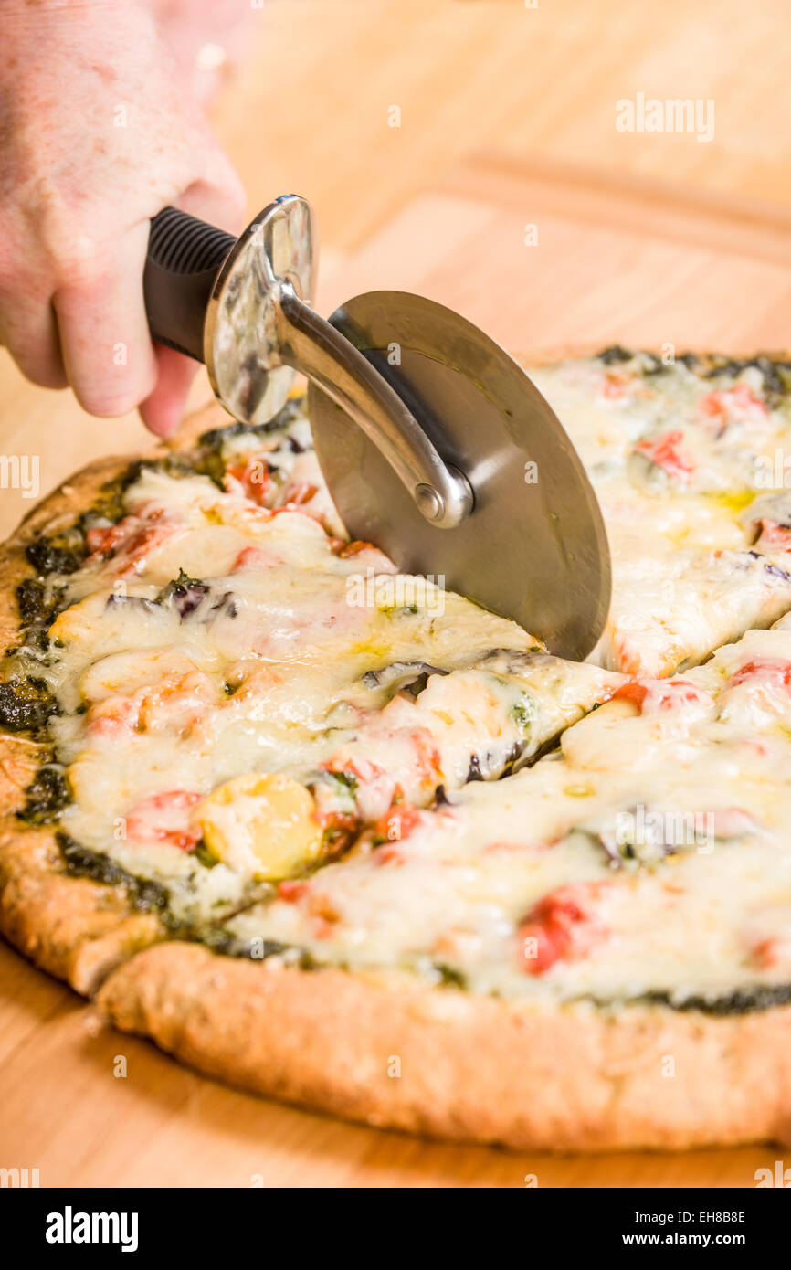 Woman using a pizza cutter to slice a homemade freshly-baked ...