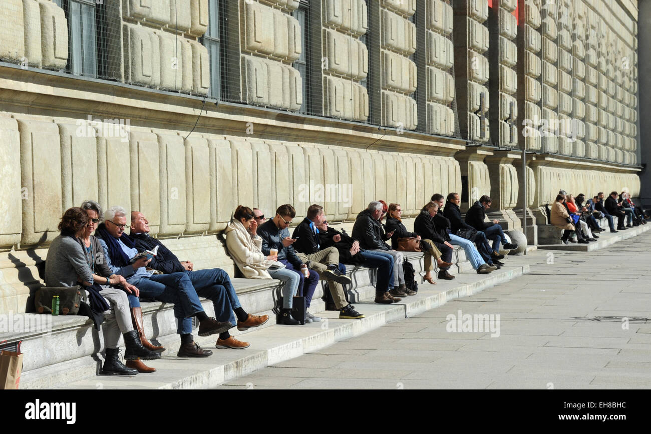 Munich, Germany. 7th Mar, 2015. People sit outside on stone benches of ...