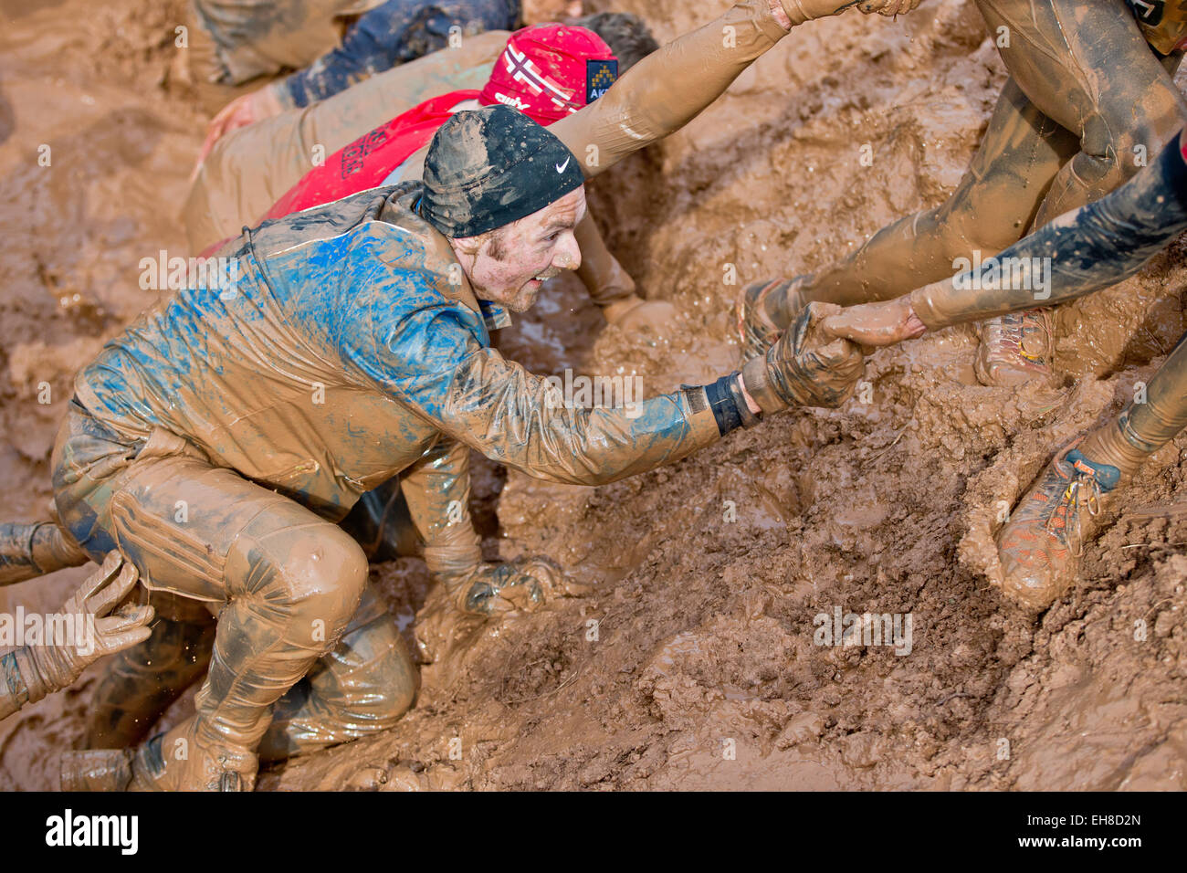 Participants help each other out of a mud pit during the extreme course ...