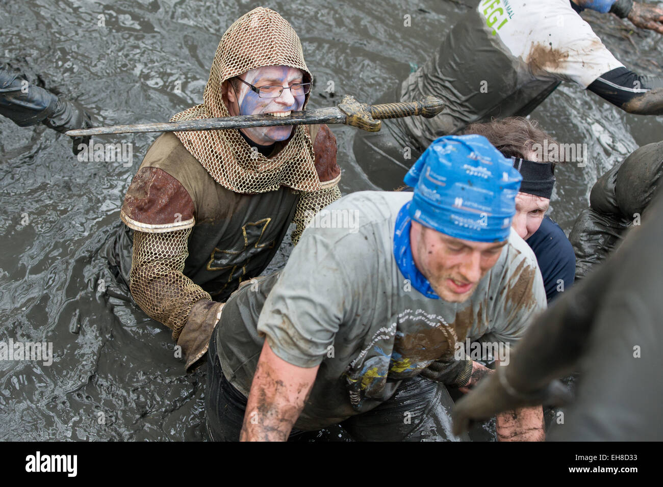 Participants help each other out of a muddy river during the extreme ...