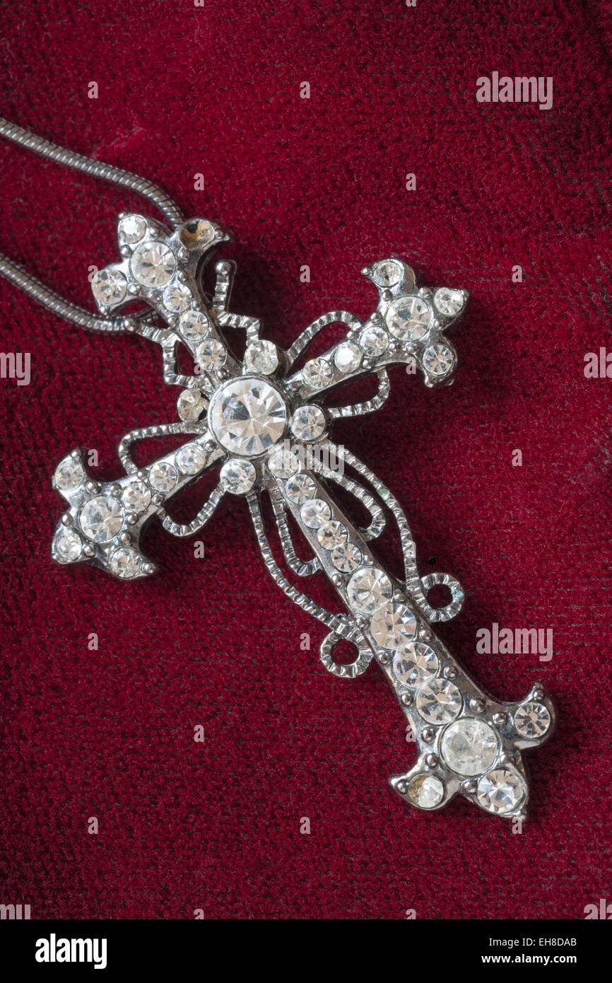 Sparkling decorative cross necklace on burgundy red velvet background ...
