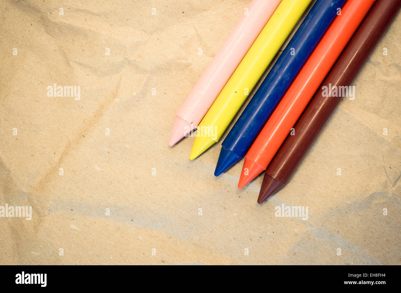 set of lined up colored wax crayons close up on a natural recycled ...