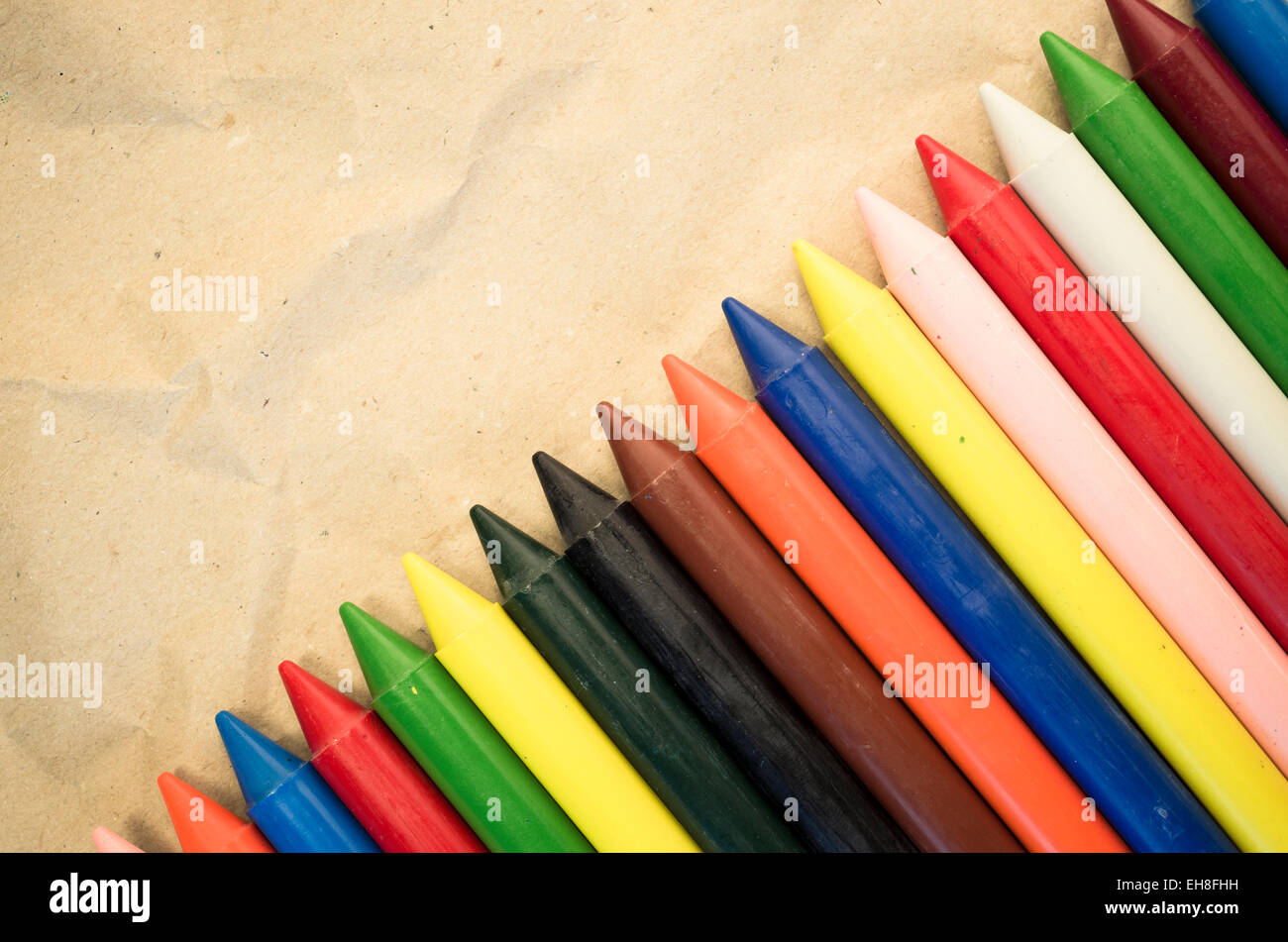 set of lined up colored wax crayons close up on a natural recycled ...