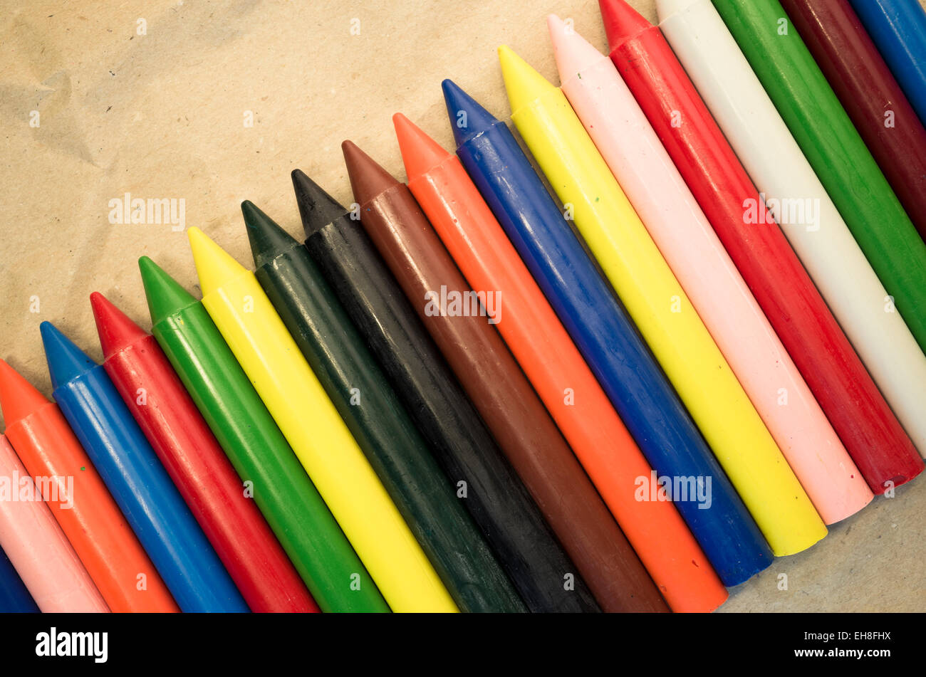 set of lined up colored wax crayons close up on a natural recycled ...