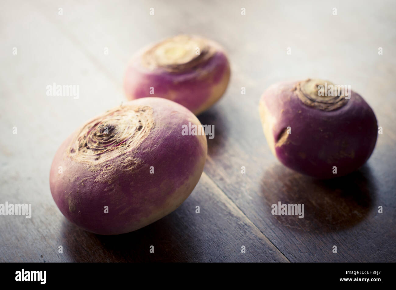 three turnip on an old wood table top surface with deep shadows Stock ...