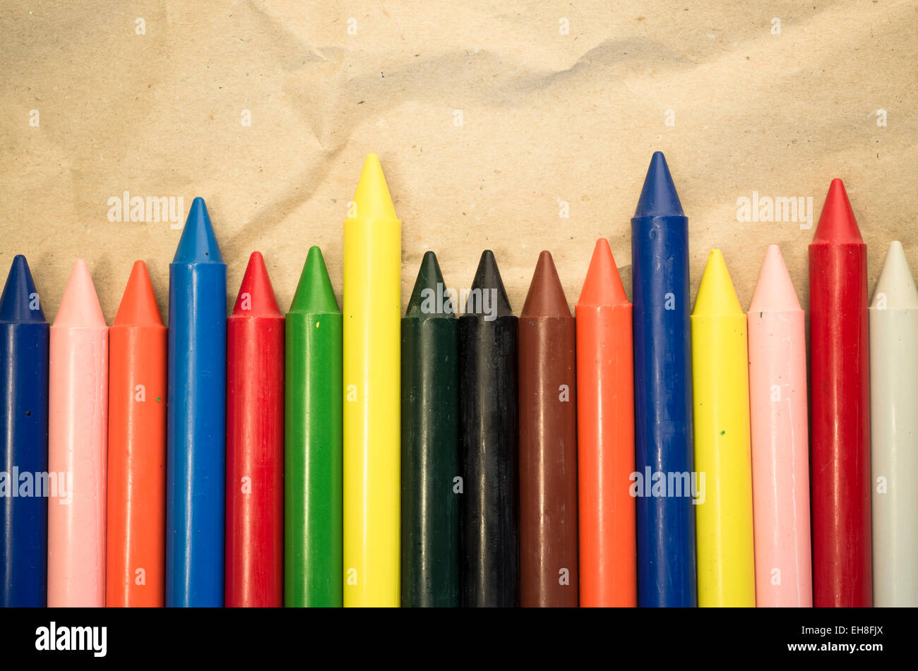 set of lined up colored wax crayons close up on a natural recycled ...