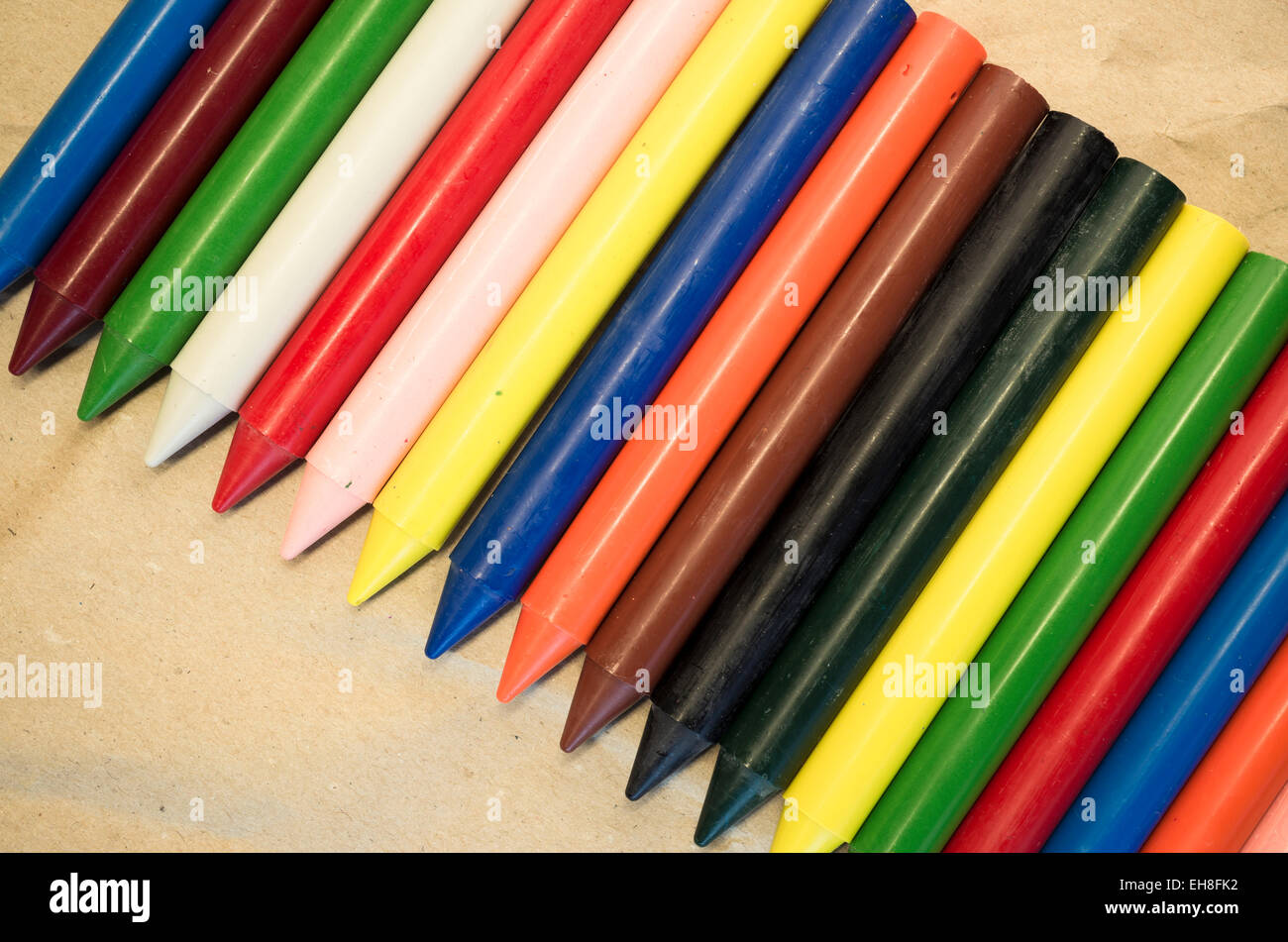 set of lined up colored wax crayons close up on a natural recycled ...