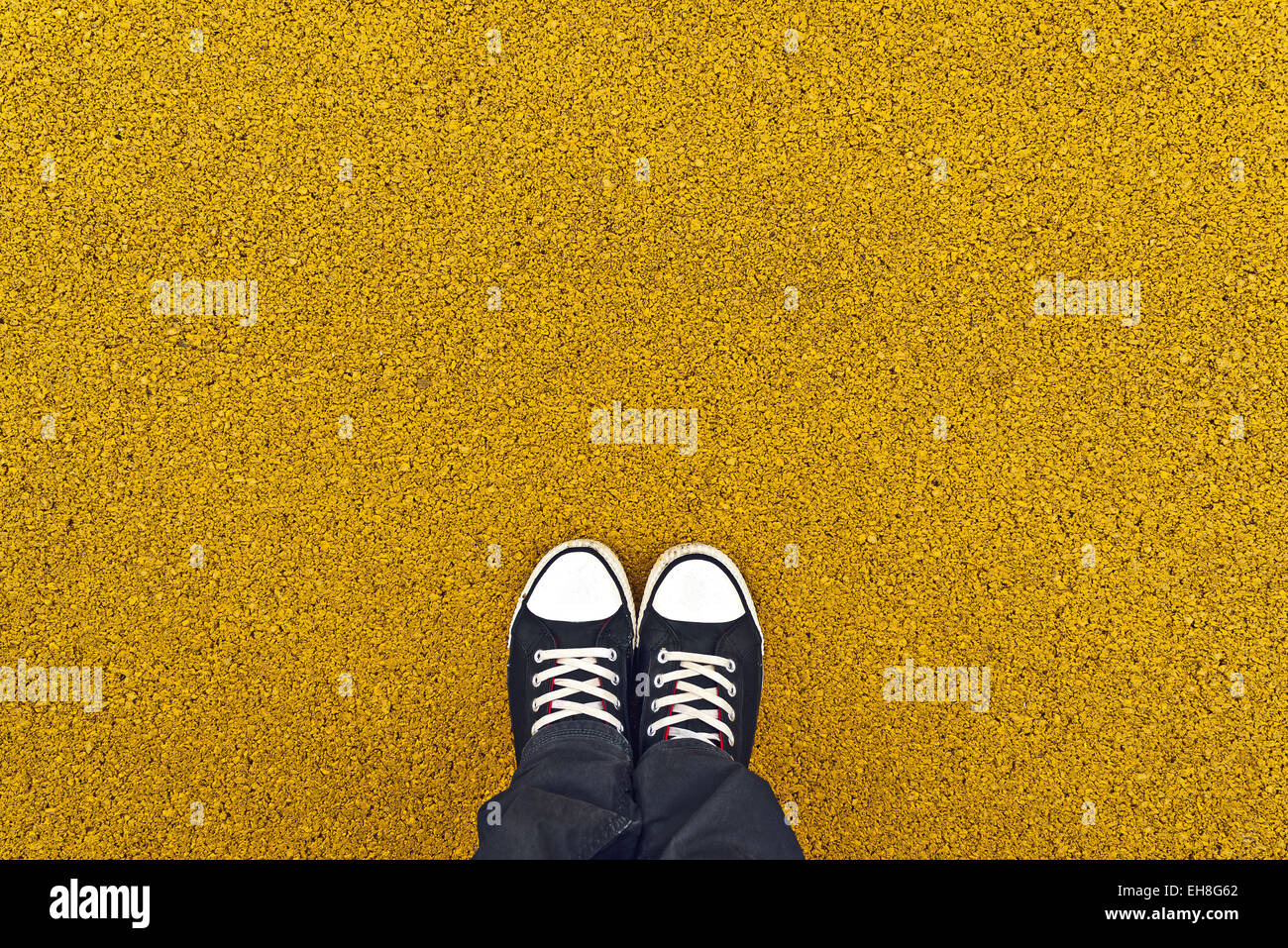 Sneakers from above. Man standing at yellow asphalt pavement as copy ...