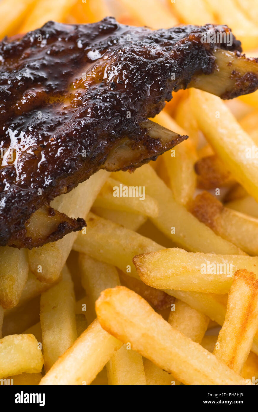 Barbecue ribs on french fries close up Stock Photo - Alamy