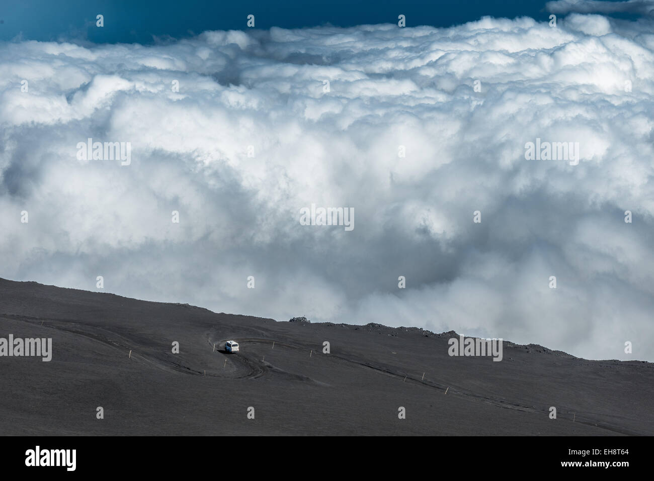Driving up on Lava Road to Etna Volcano with Clouds in the background ...