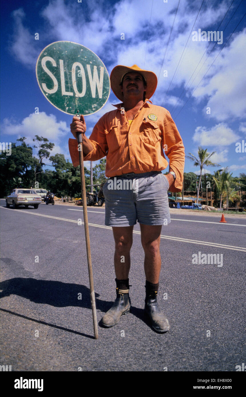 A flagman holds a traffic sign to slow cars down at a crossing for ...
