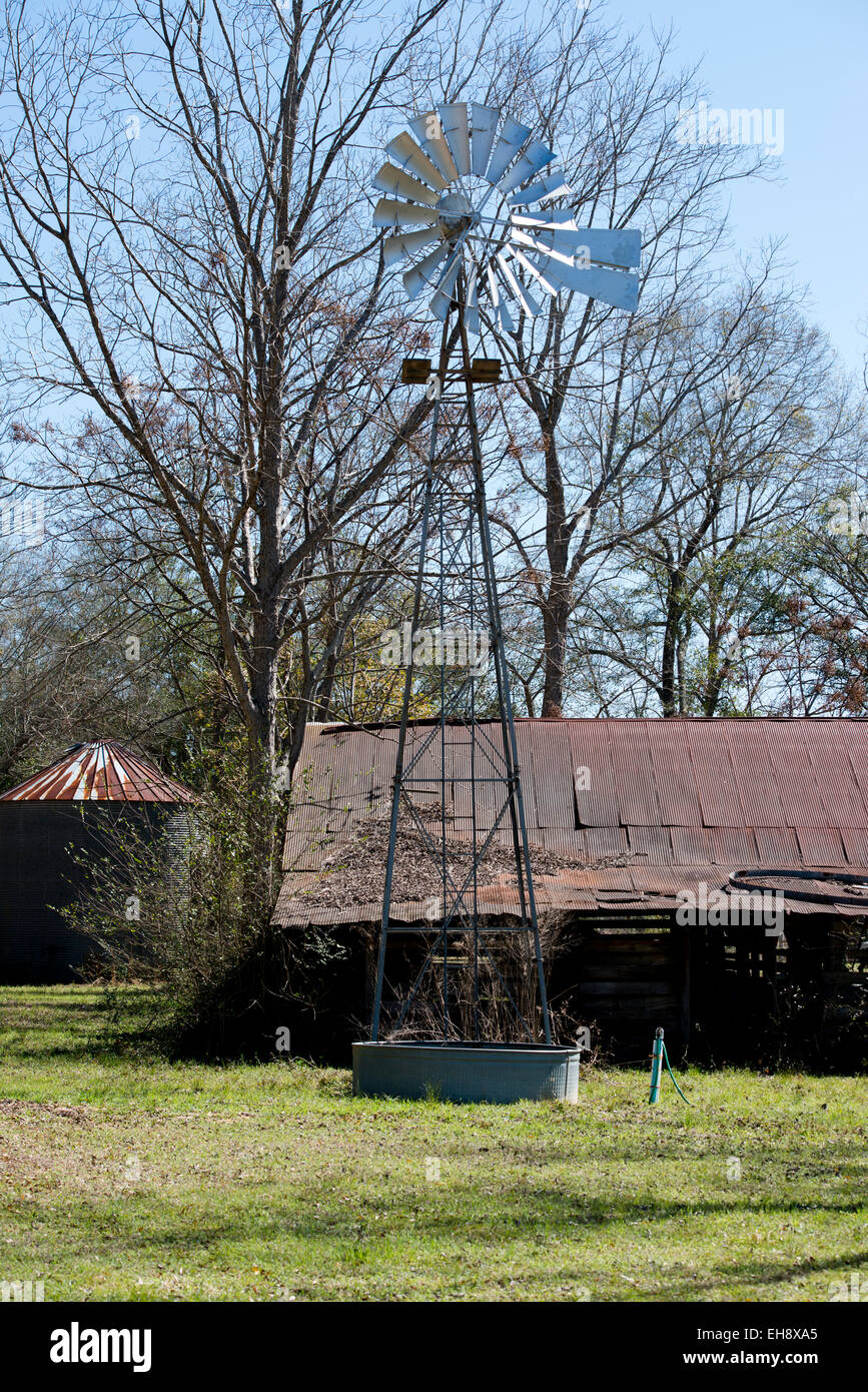 Windmill, barn and grain silo in a green grassy field surrounded by oak ...