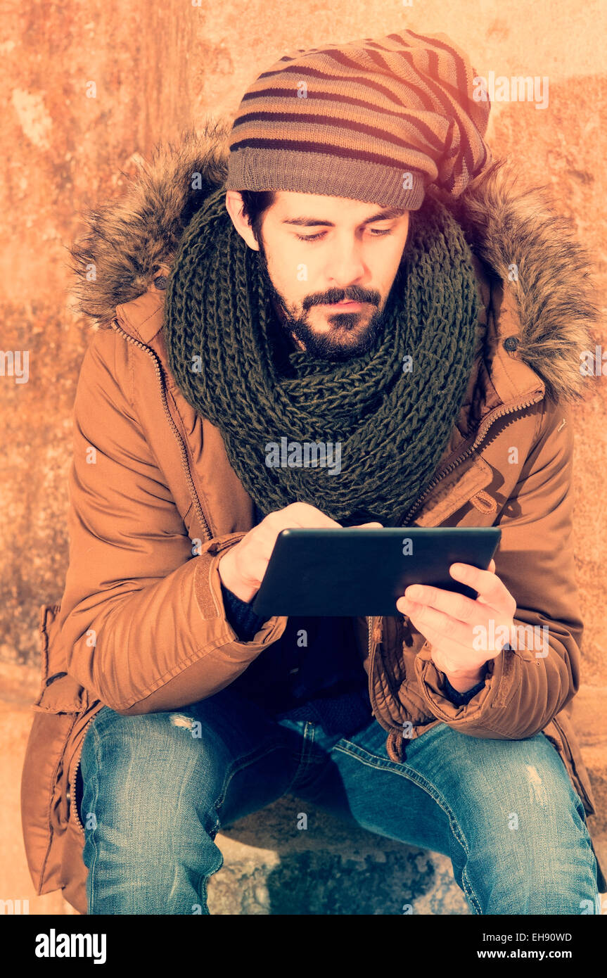young man holding a tablet in outdoor urban setting warm tone filter ...