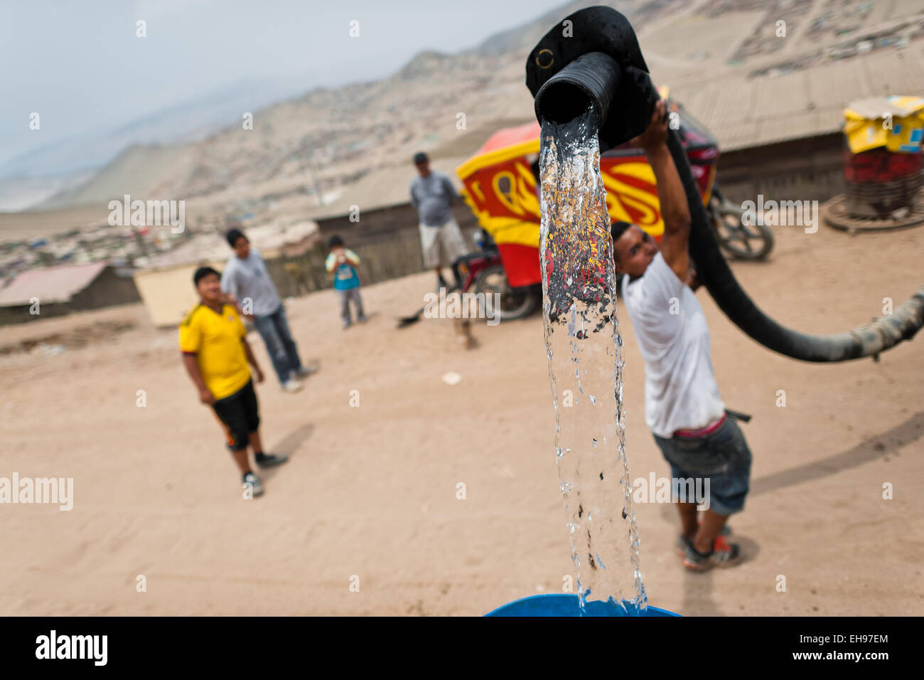 A Peruvian water distribution worker with a hose splashes drinking ...