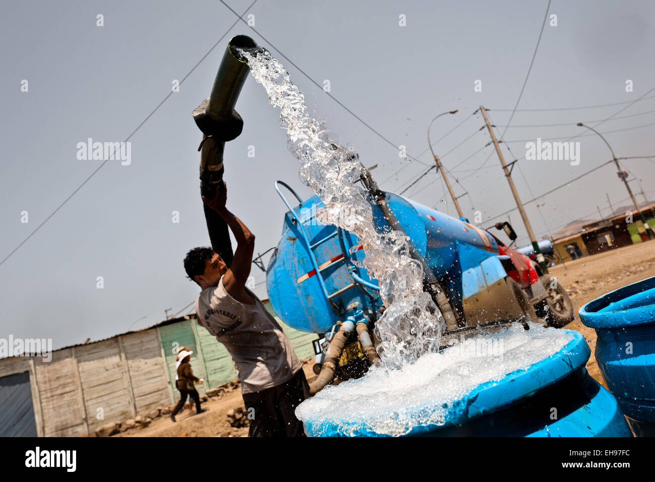 A Peruvian water distribution worker with a hose splashes drinking ...