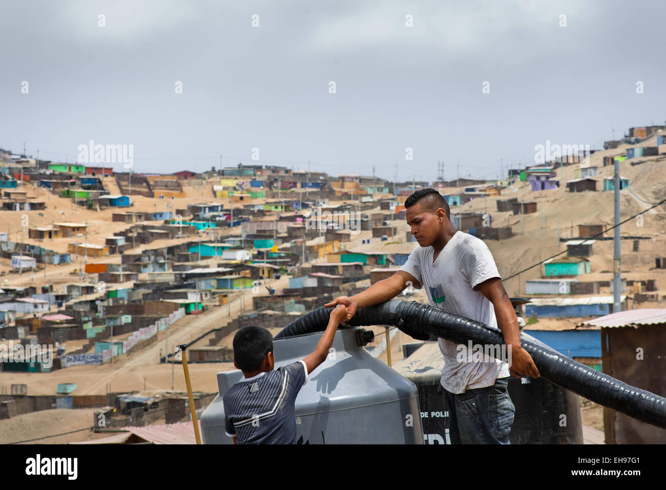 A Peruvian boy pays a water distribution worker to fill a tank with ...