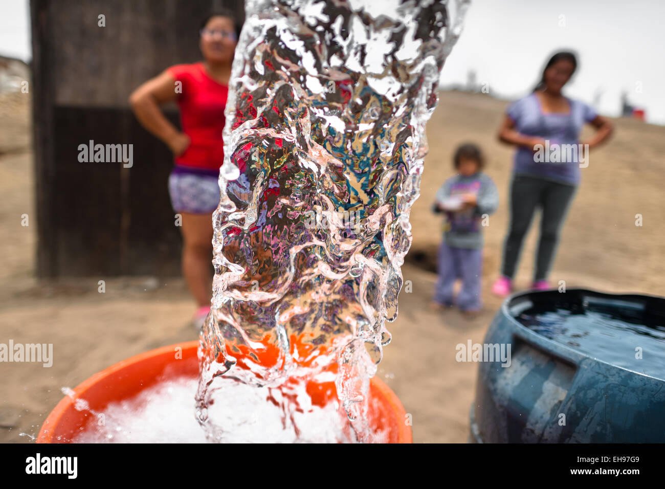 A splashing stream of drinking water falls into a plastic barrel in ...