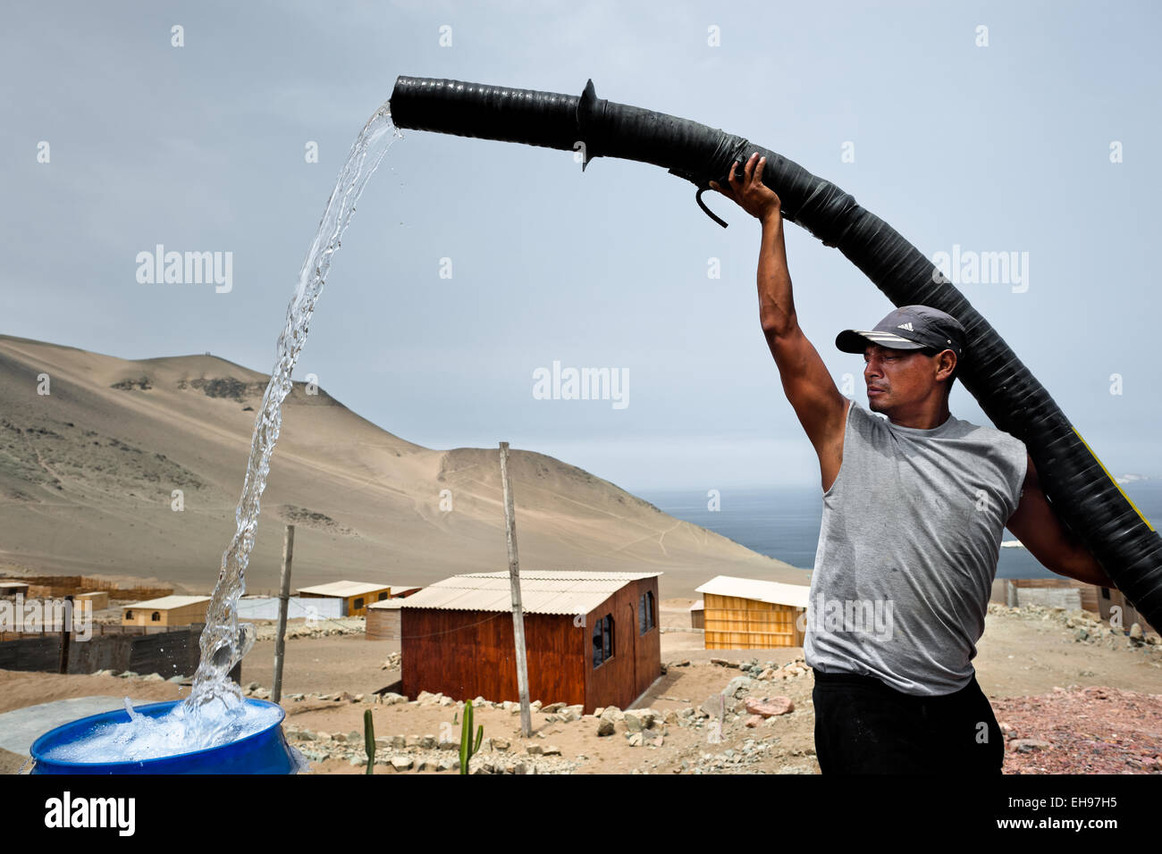 A Peruvian water distribution worker with a hose splashes drinking ...