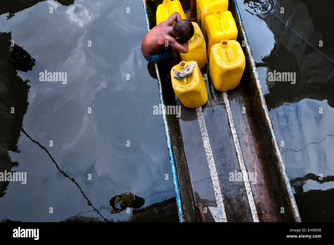 A Colombian boy sleeps in a canoe, filled by barrels of safe drinking ...
