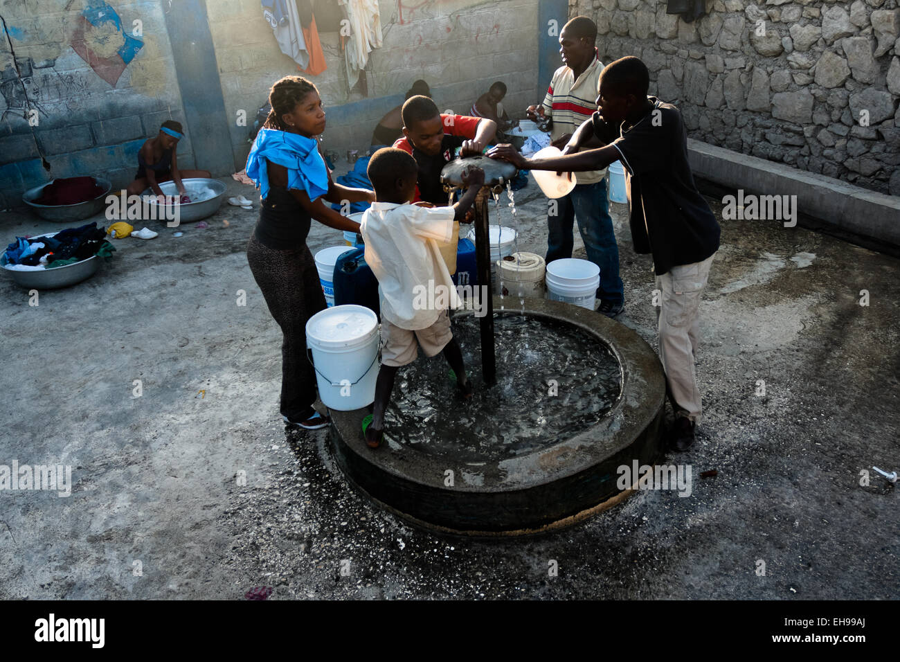 Haitians fill plastic barrels with safe drinking water from a public ...