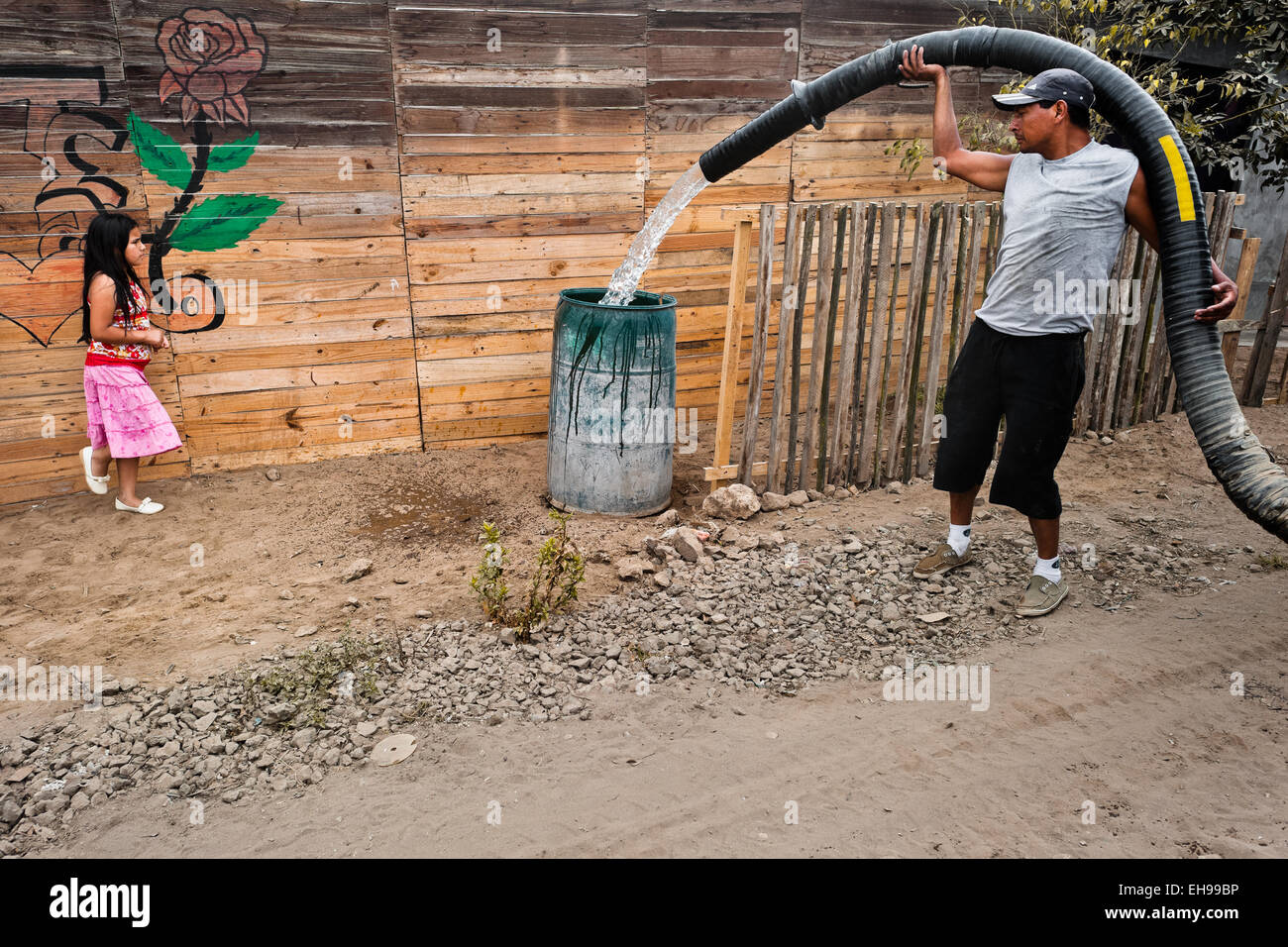 A Peruvian water distribution worker with a pipe splashes drinking ...