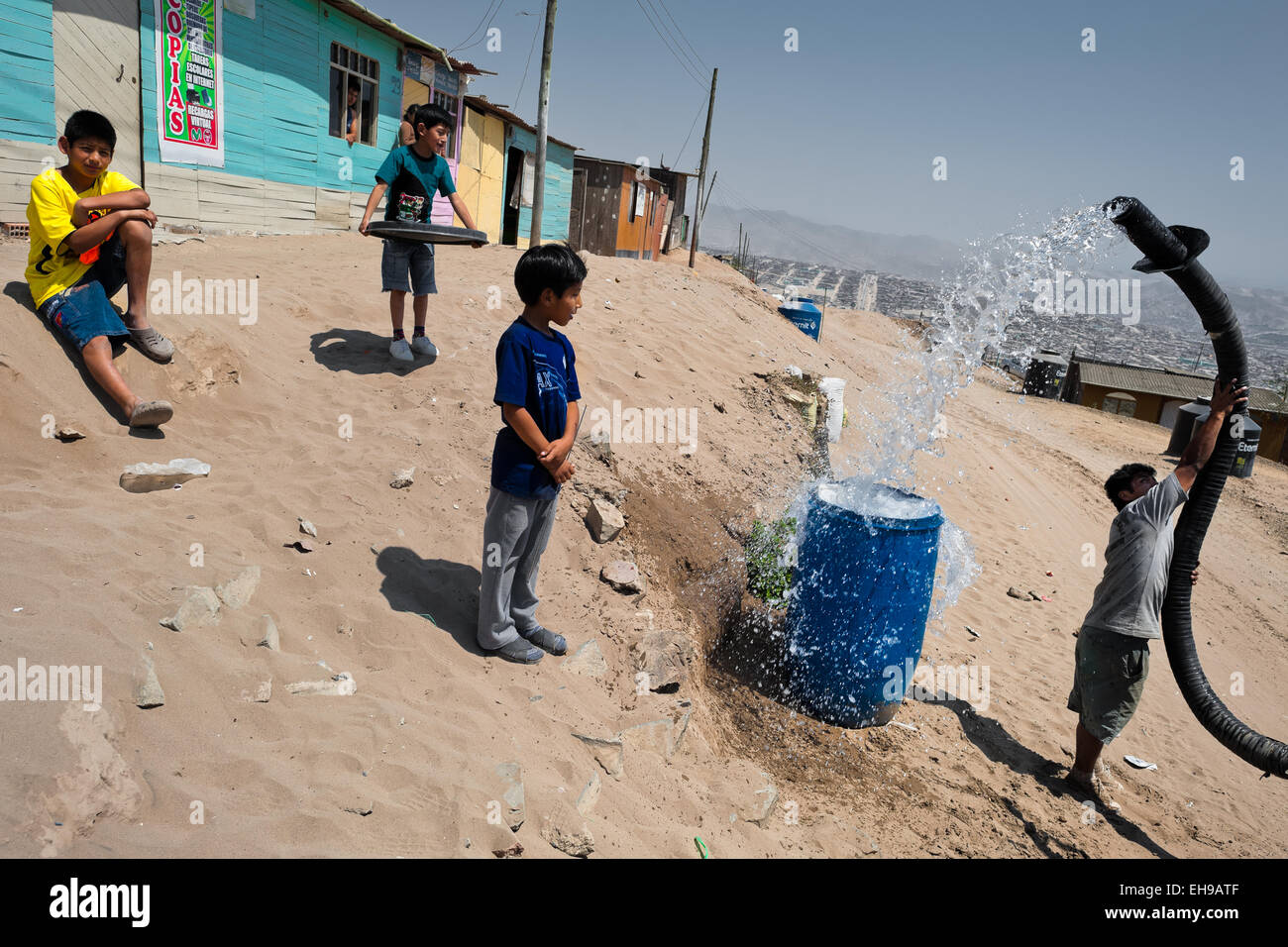 A Peruvian water distribution worker with a pipe splashes drinking ...